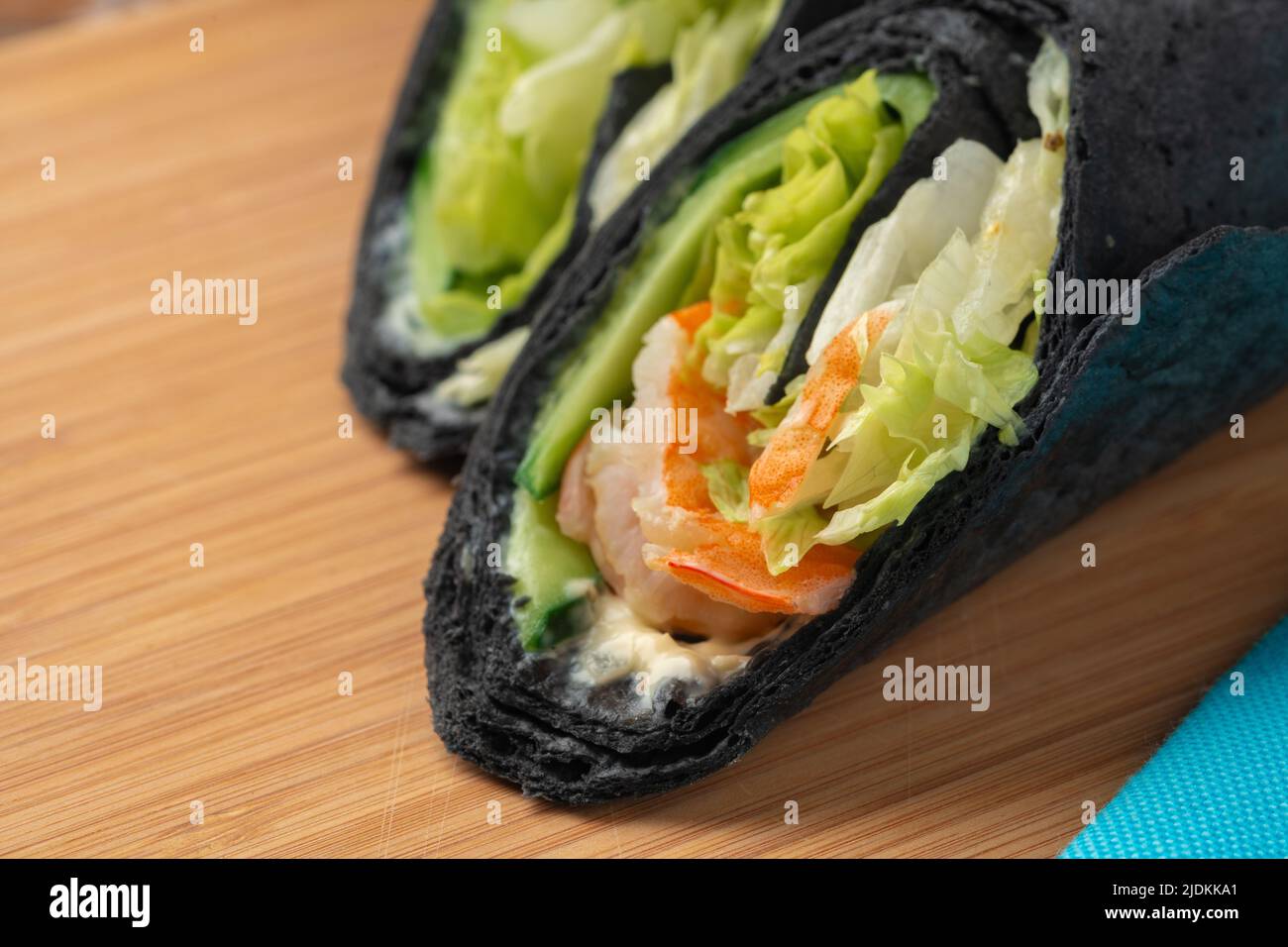 Tortilla wrap with shrimps and vegetables on wooden background Stock ...