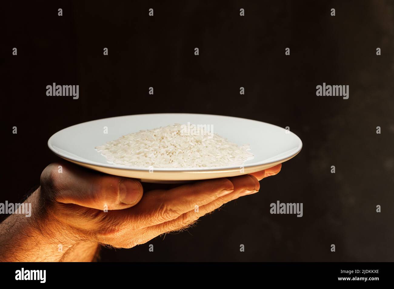 Hands holding a heap of dry rice grain on black background Stock Photo ...