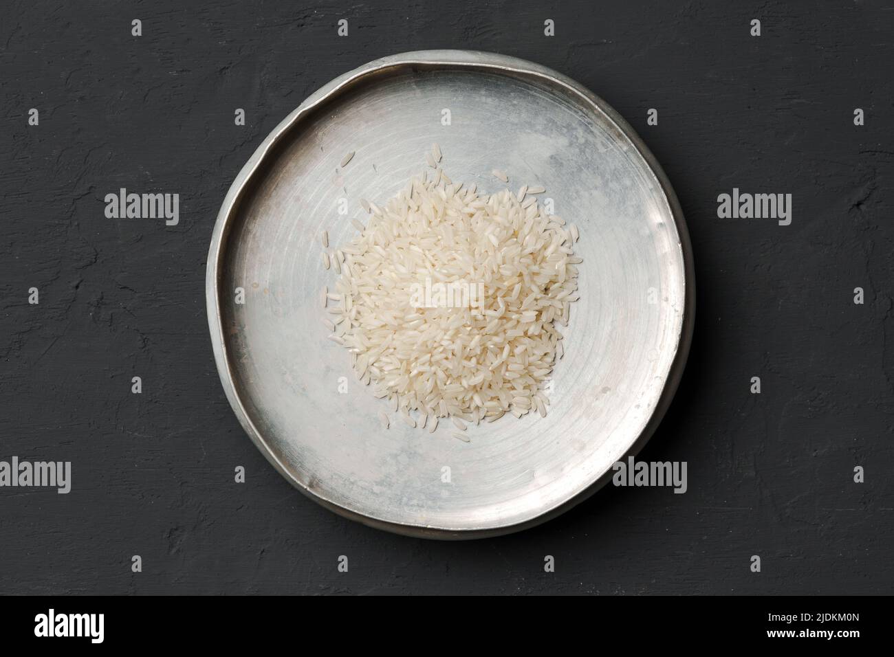 Heap of dry rice in a bowl on black background, lack of food, hunger ...