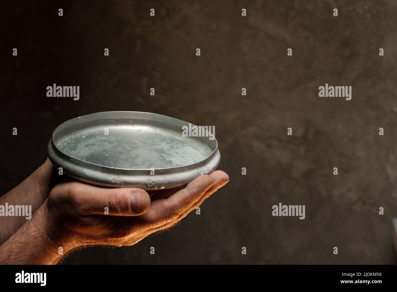 Male hands holding empty plate on dark background, lack of food, hunger ...