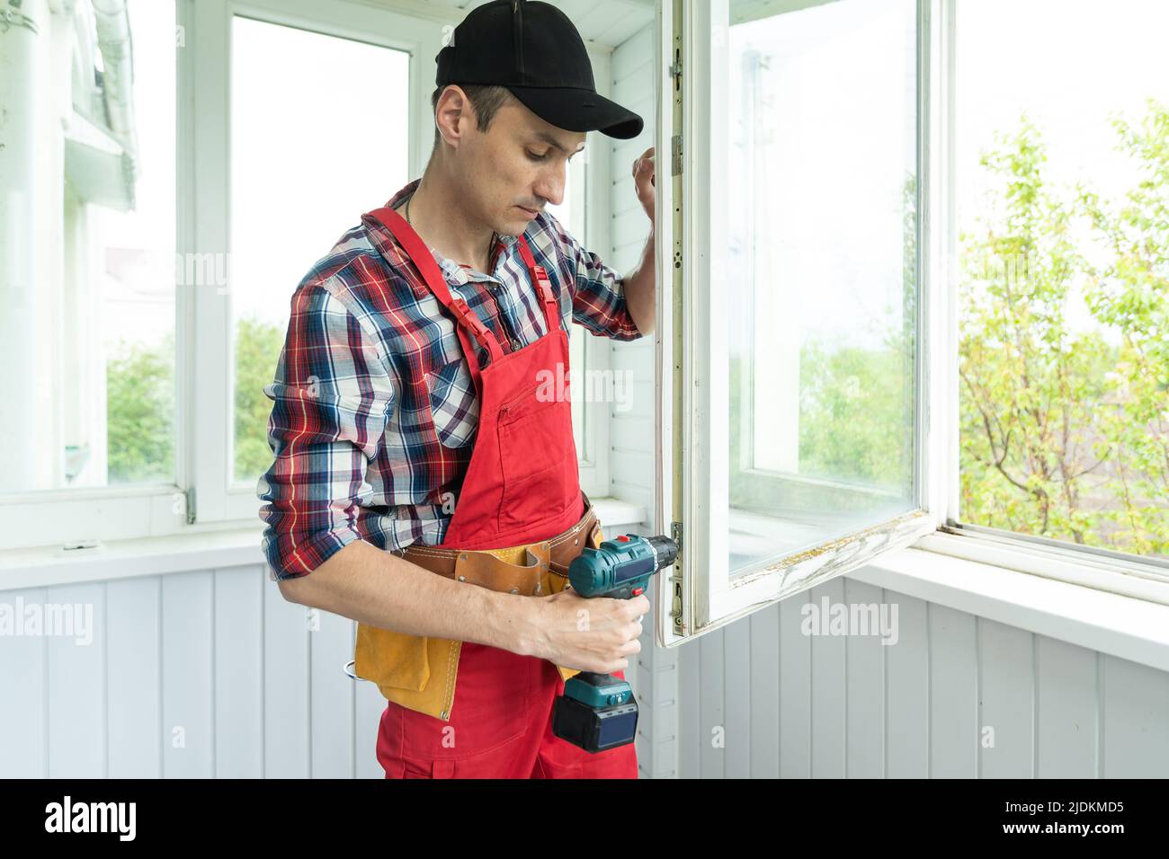 handyman adjusting white pvc plastic window indoors. worker using ...