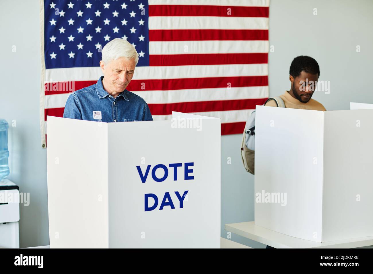 Portrait of two people in voting booths on election day against USA ...