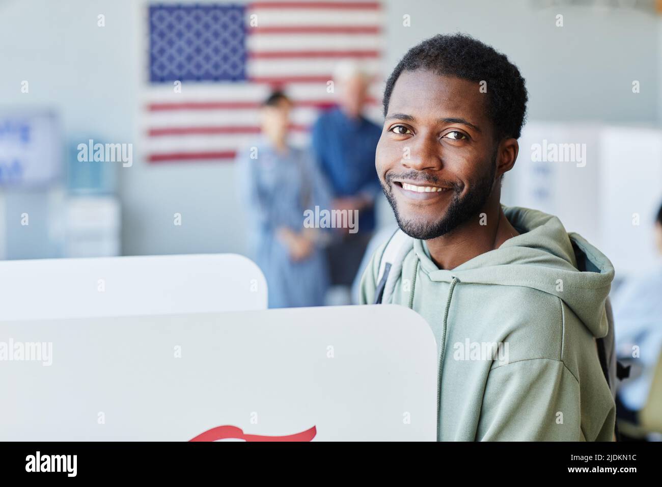 Side view portrait of young black man voting in booth on election day ...
