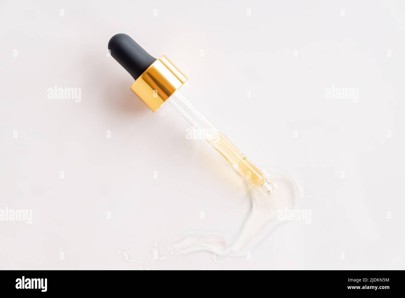 beauty face oil dripping from gold dropper on gray background. Skin ...