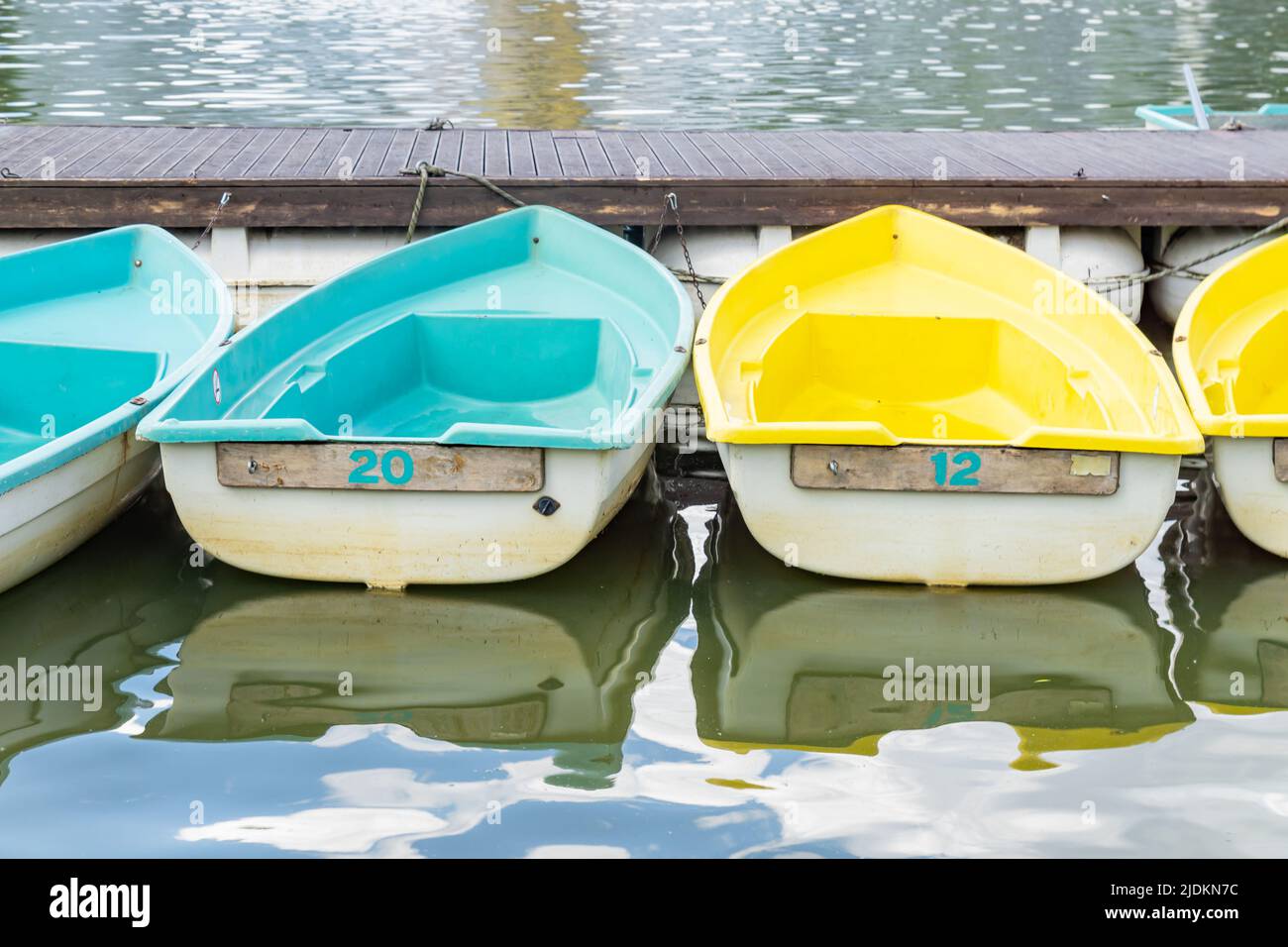 Blue and yellow boats float on the water next to the pier. Boat station ...