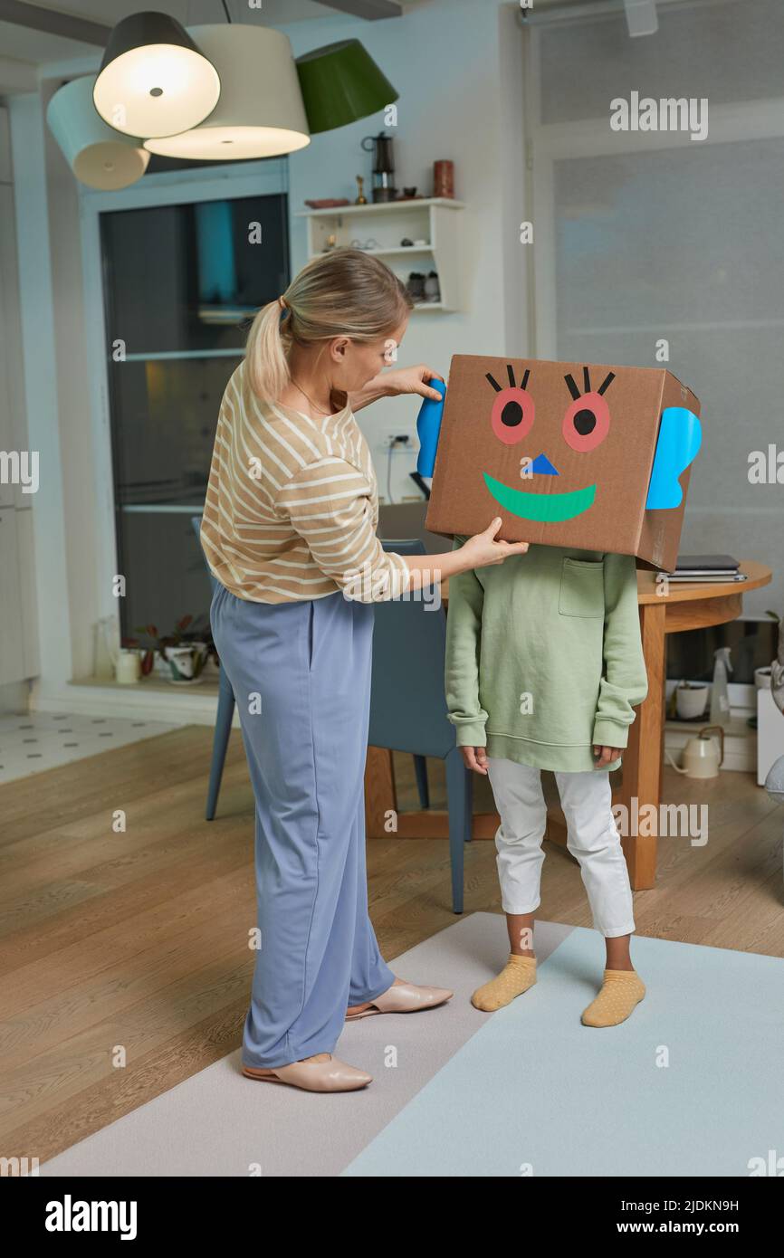 Vertical full length portrait of smiling mother helping daughter with ...