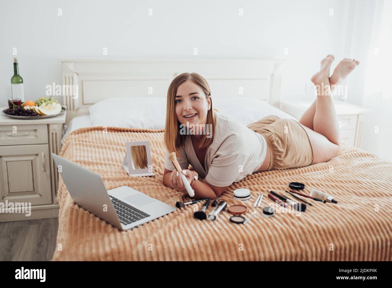 Young Caucasian Woman Laying on the Bed with Cosmetics and Looking Into ...