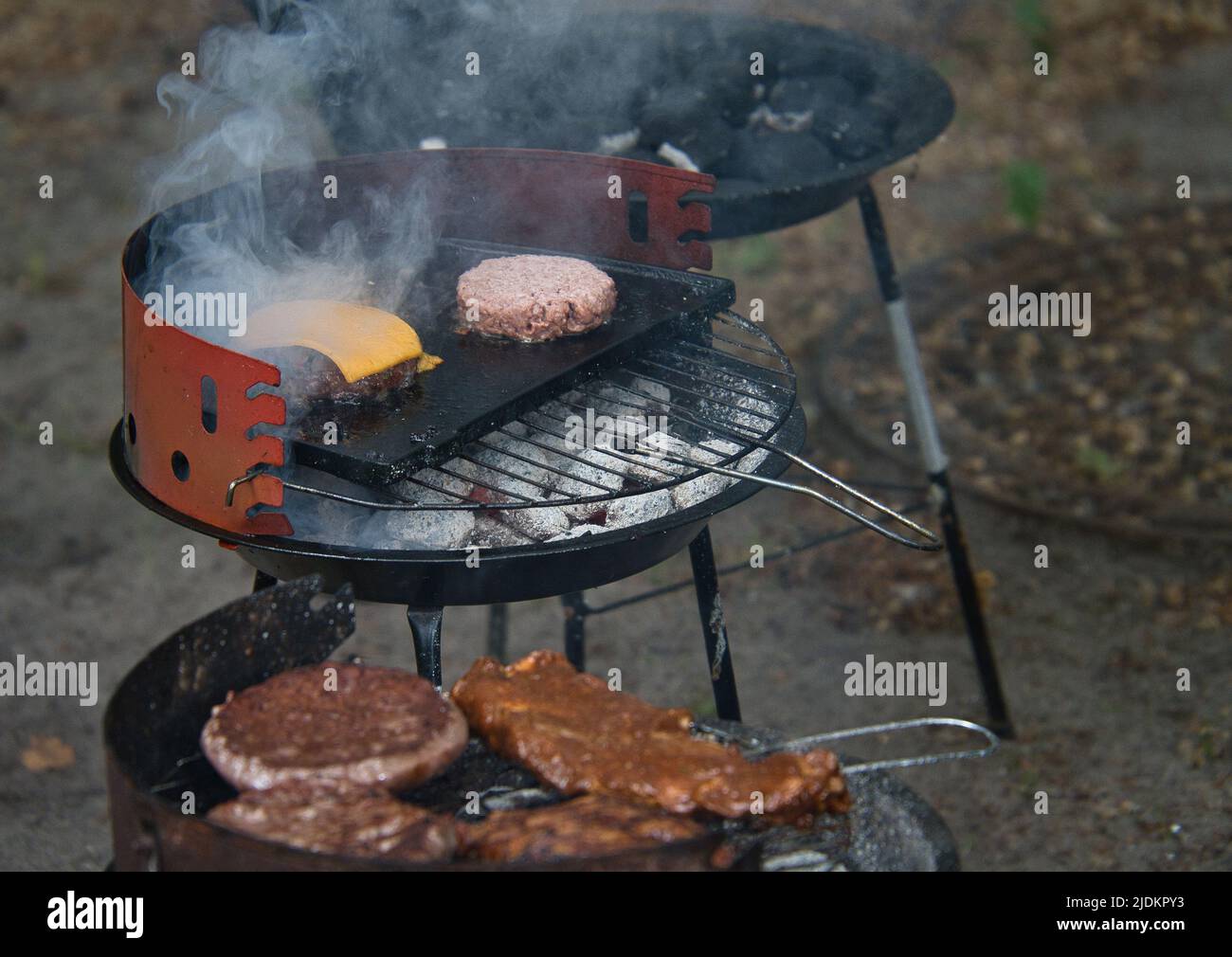 Grill with coal, grate and meat. Burger with cheese in the preparation ...