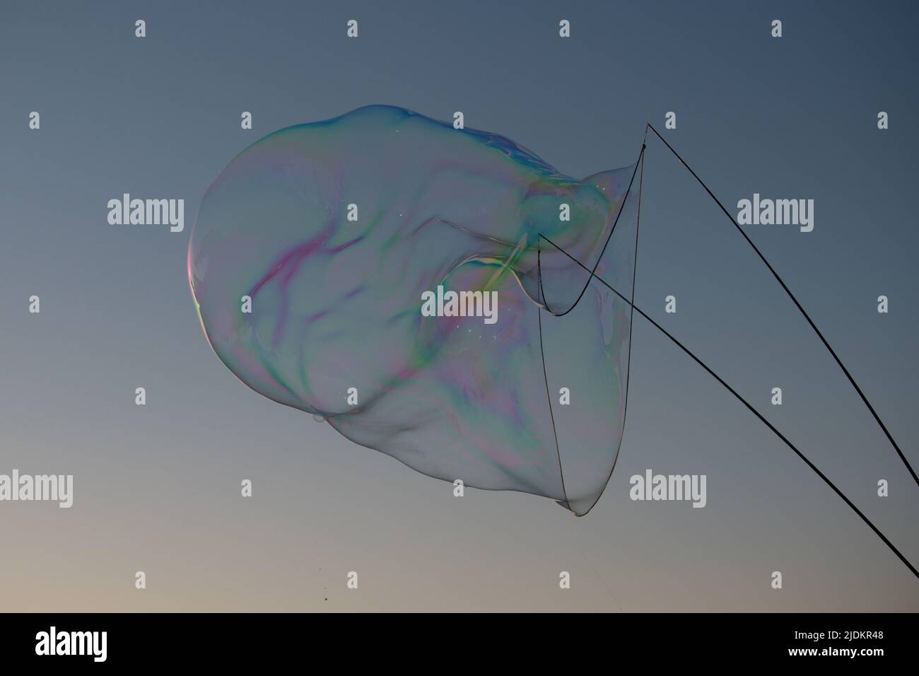 Big soap bubbles on sky background. Bubble making with rope and sticks ...