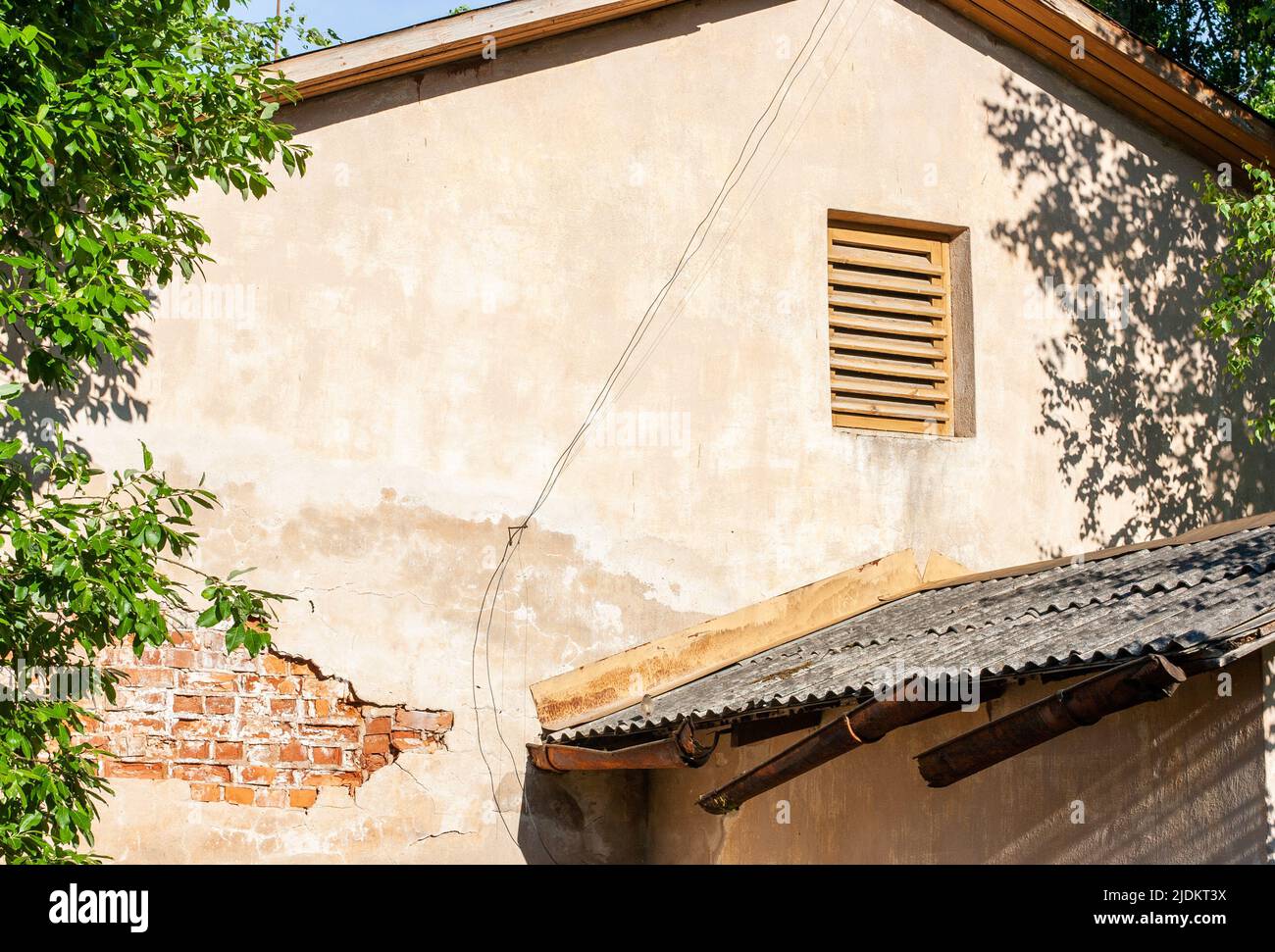 The wall of the house with a dilapidated plaster, with orange bricks at ...