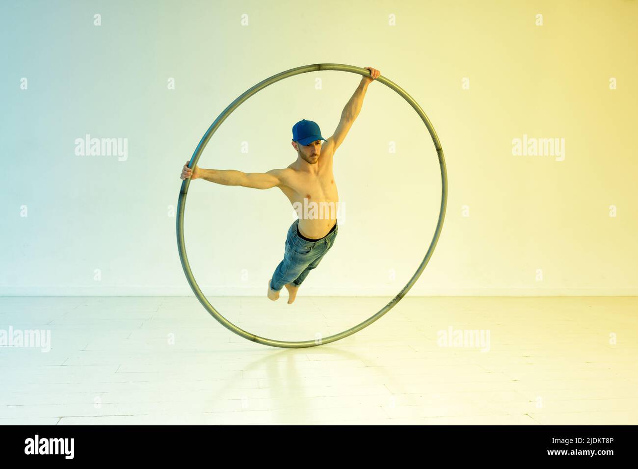 Acrobat training on a spinning cyr wheel performing a superman trick ...