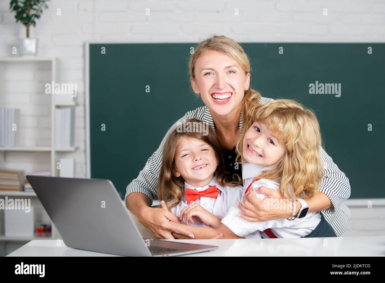 Happy school kids and teacher learning study in class. Teacher helping ...