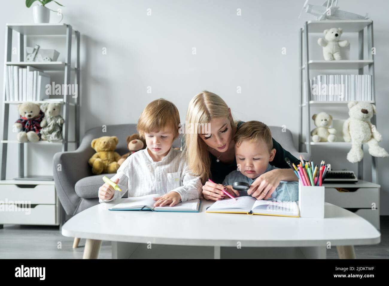 Mother and two son together draw, paint. Mom helps the children boys ...