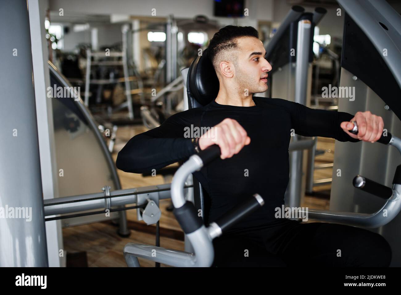 Muscular arab man training and doing workout on fitness machine in ...