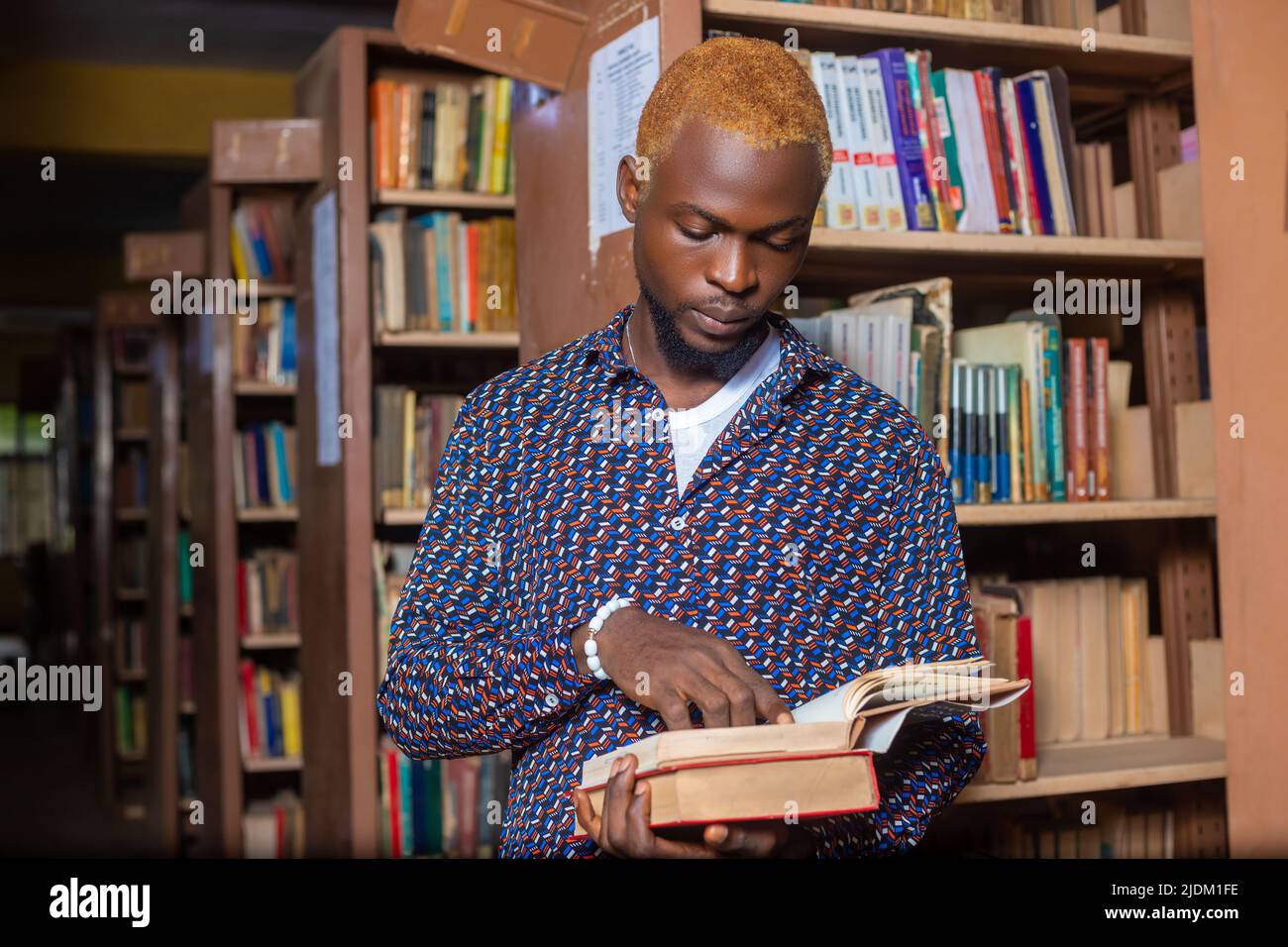 Young man reading book in library Stock Photo - Alamy