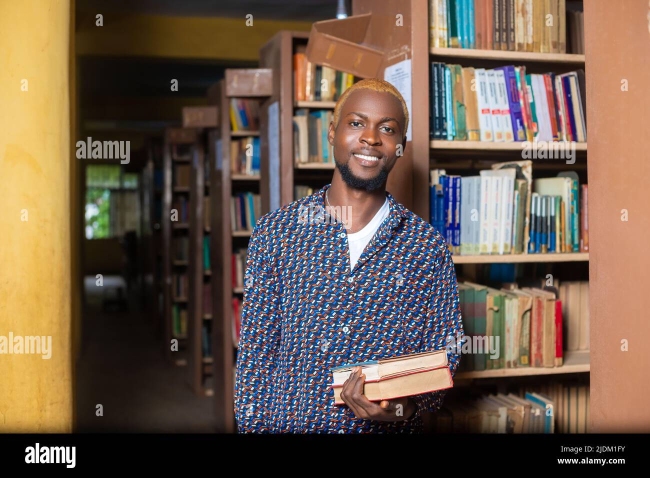Young man reading book in library Stock Photo - Alamy