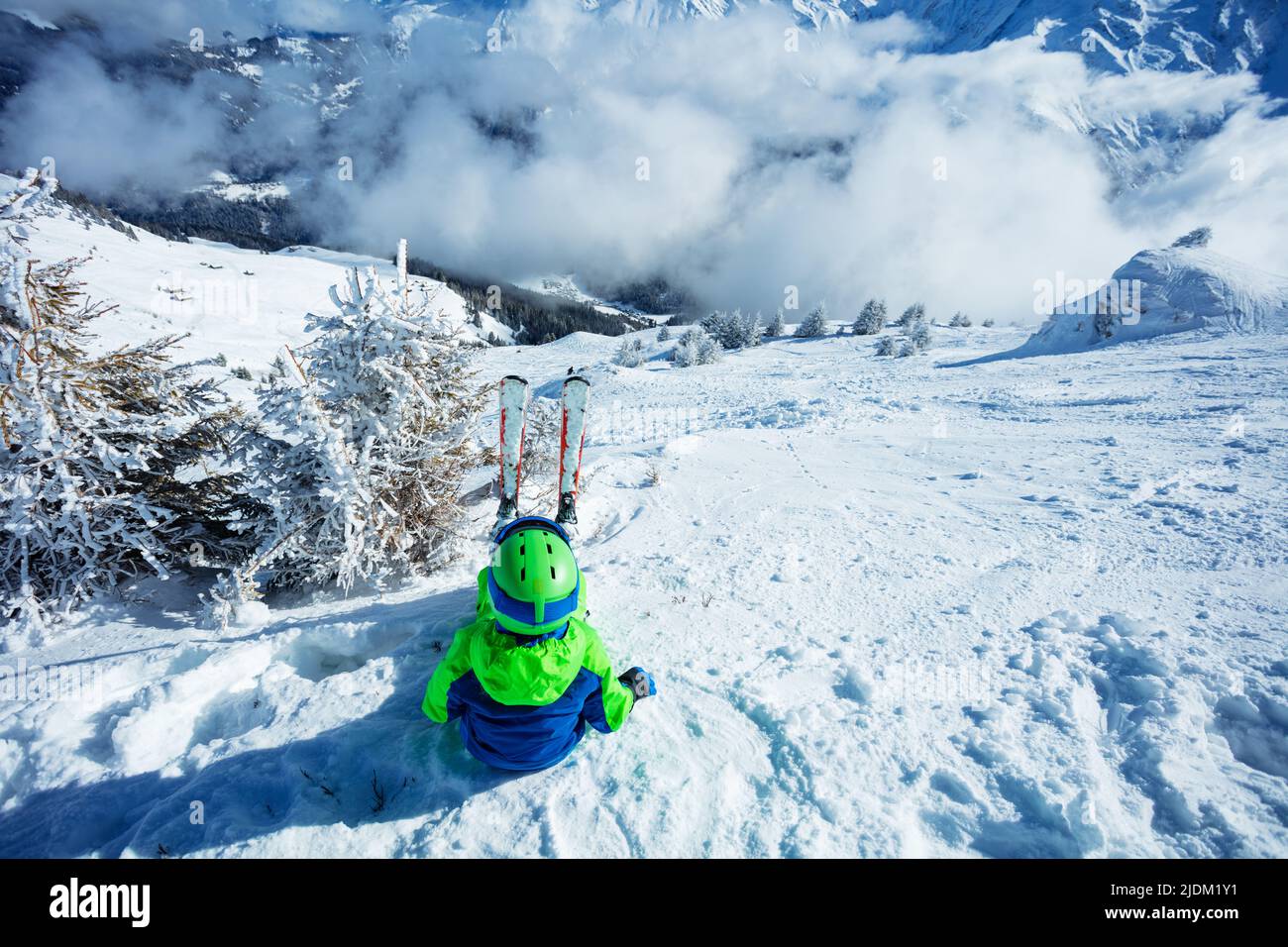 Boy with alpine ski sit in snow on top of steep mountain slope Stock ...