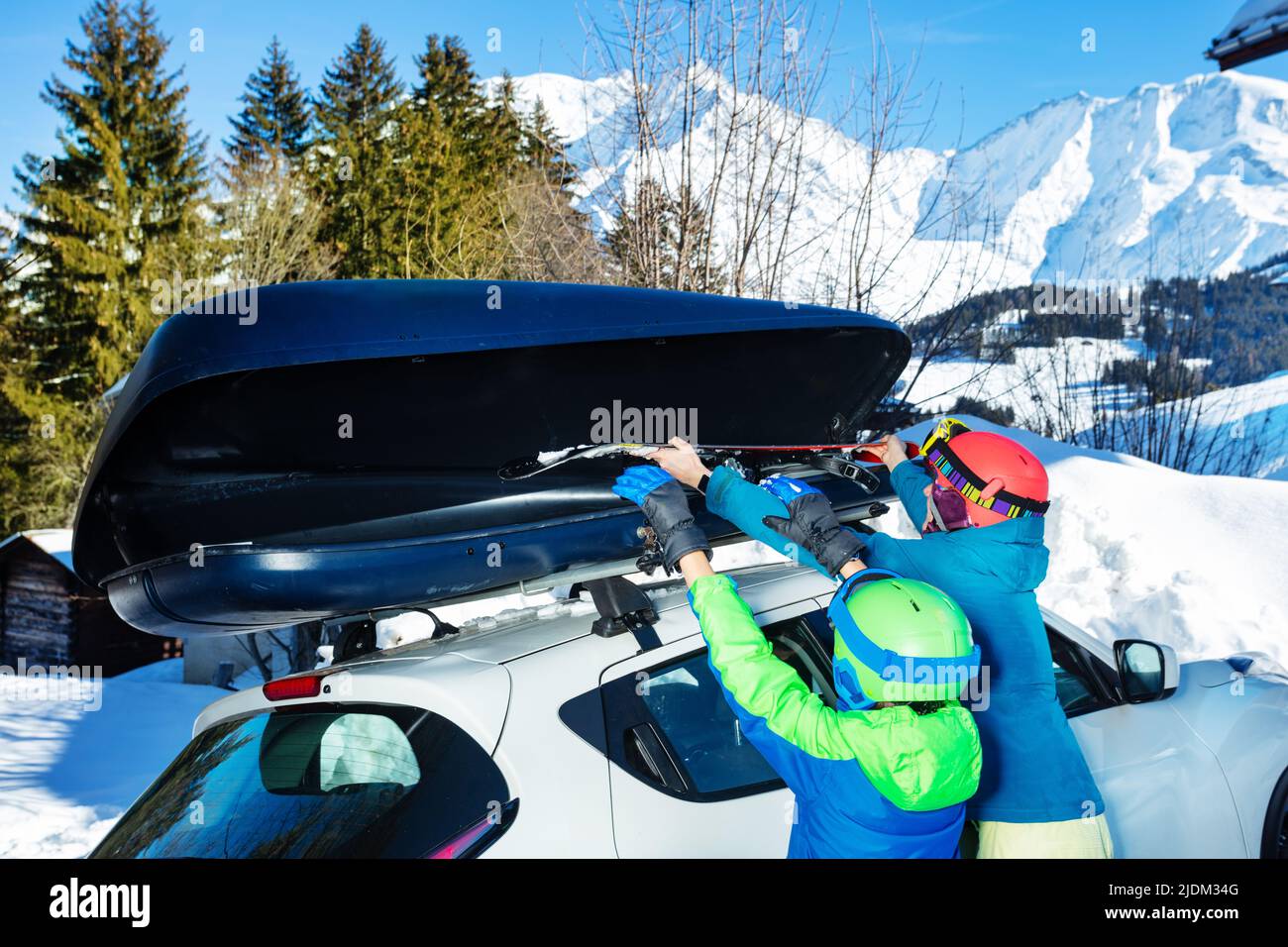 Young woman and boy put together ski in the car box, back view Stock ...