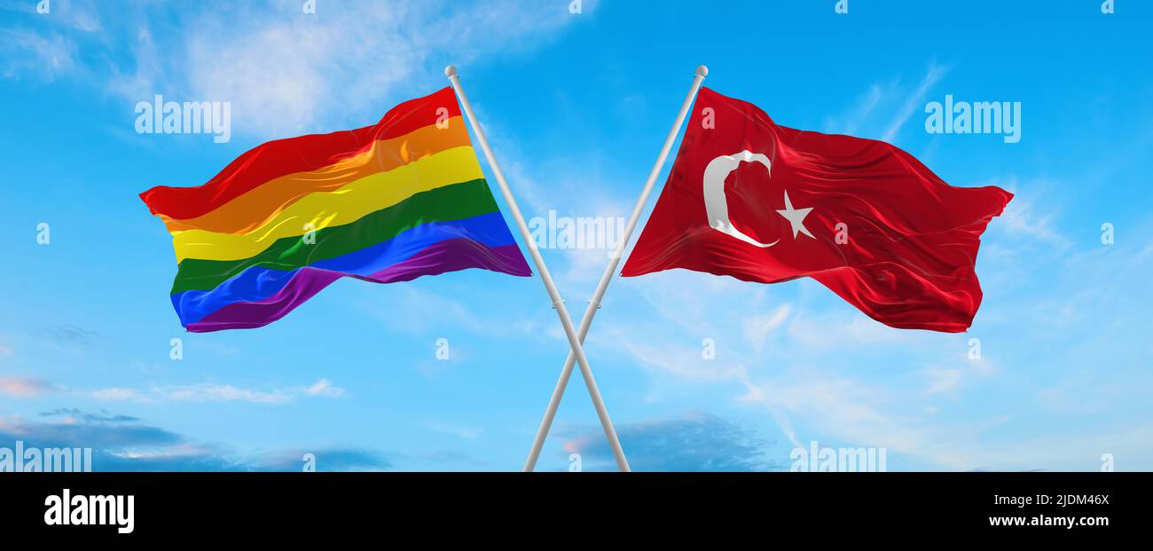 two crossed flags LGBT Pride and Turkey waving in wind at cloudy sky ...