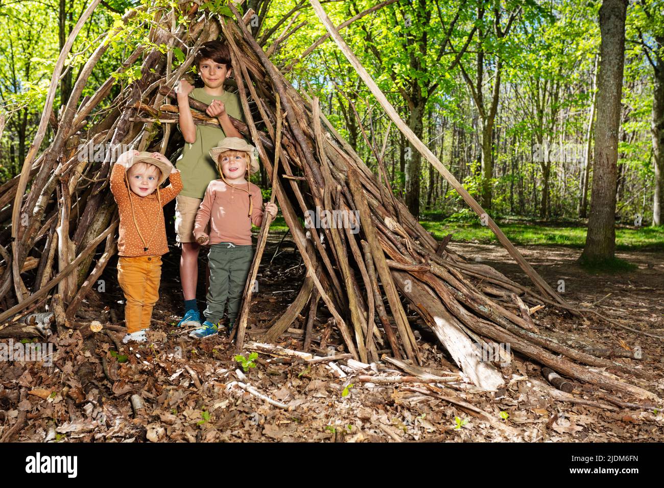 Three children boys and a girl build hut of branches Stock Photo - Alamy