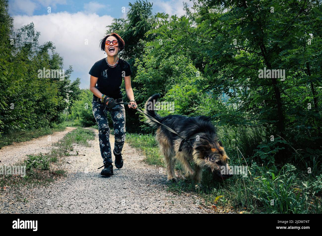 Cheerful young woman walking her dog on a leash. Friendship, leisure ...