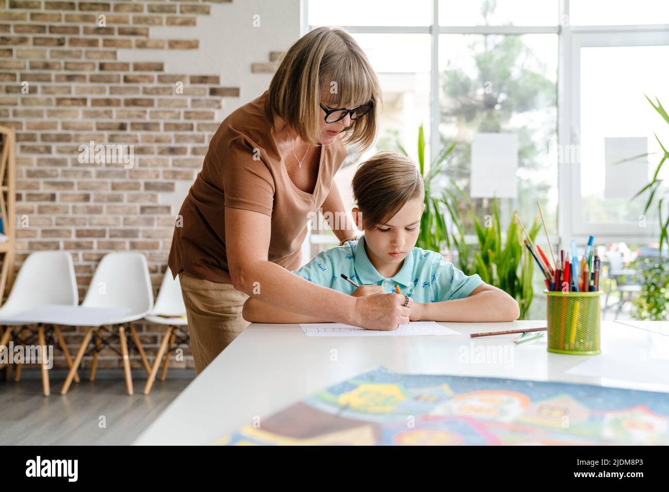 White teacher talking with her student during class in art school ...