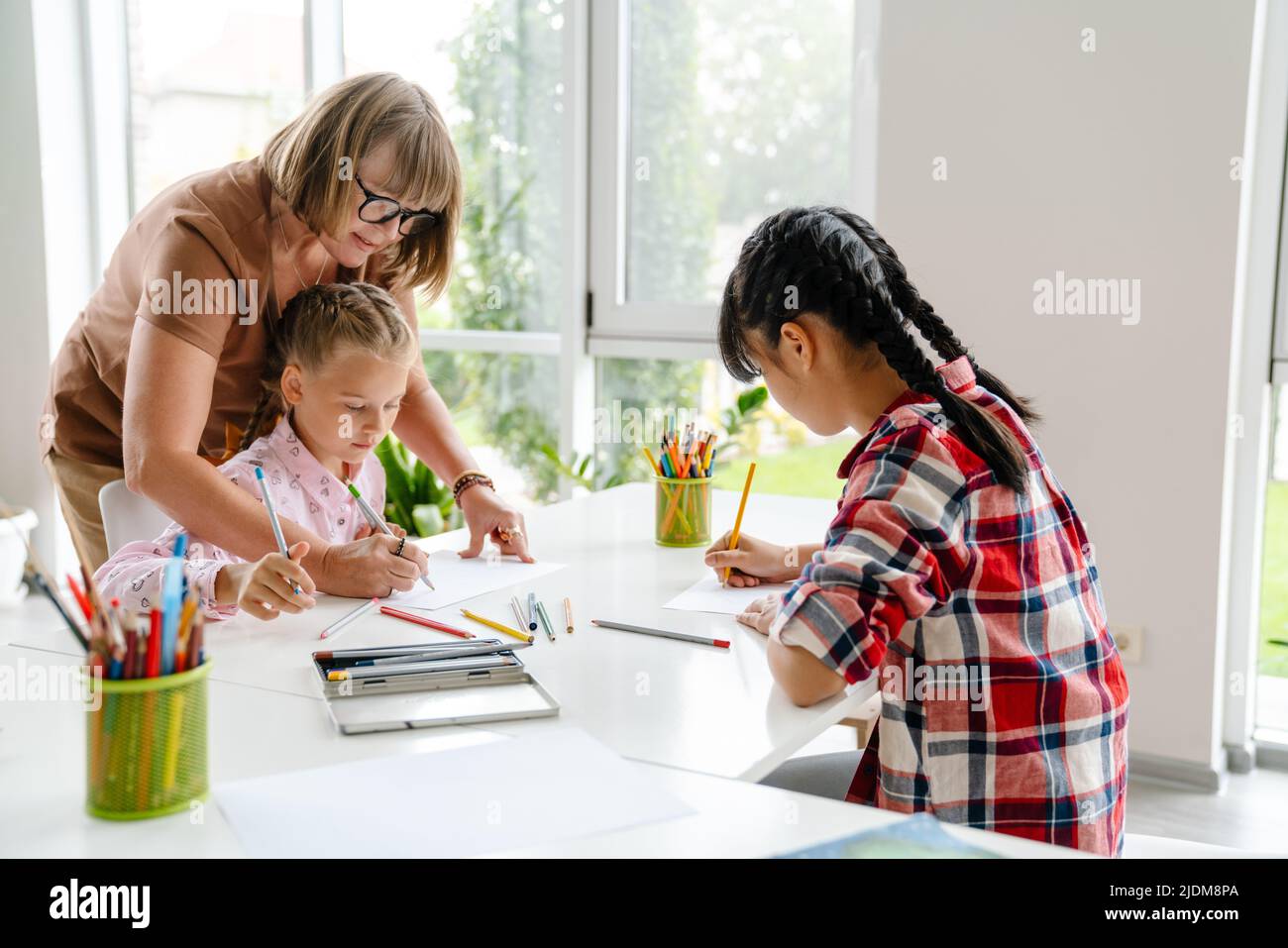 Mature teacher drawing with her pupils during class in art school ...