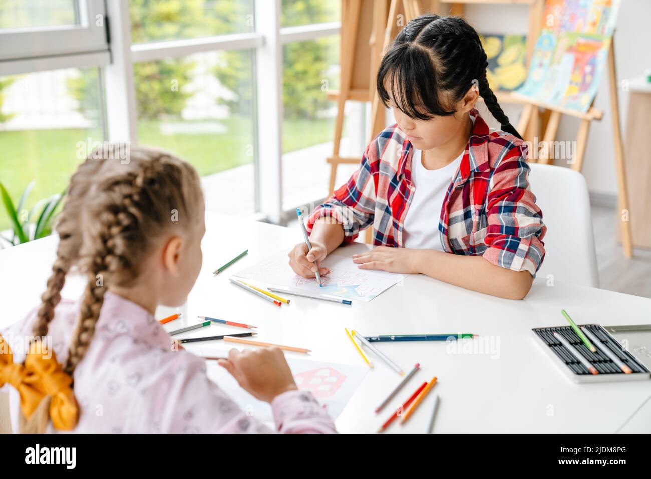Multiracial girls drawing during class in art school indoors Stock ...