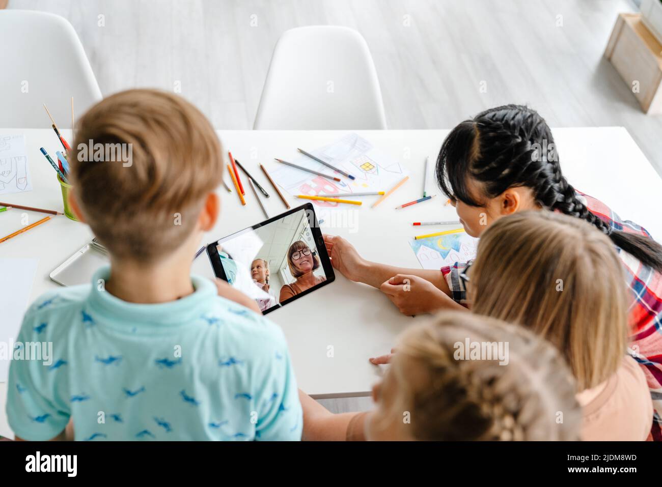 White teacher taking selfie on tablet computer with students in art ...