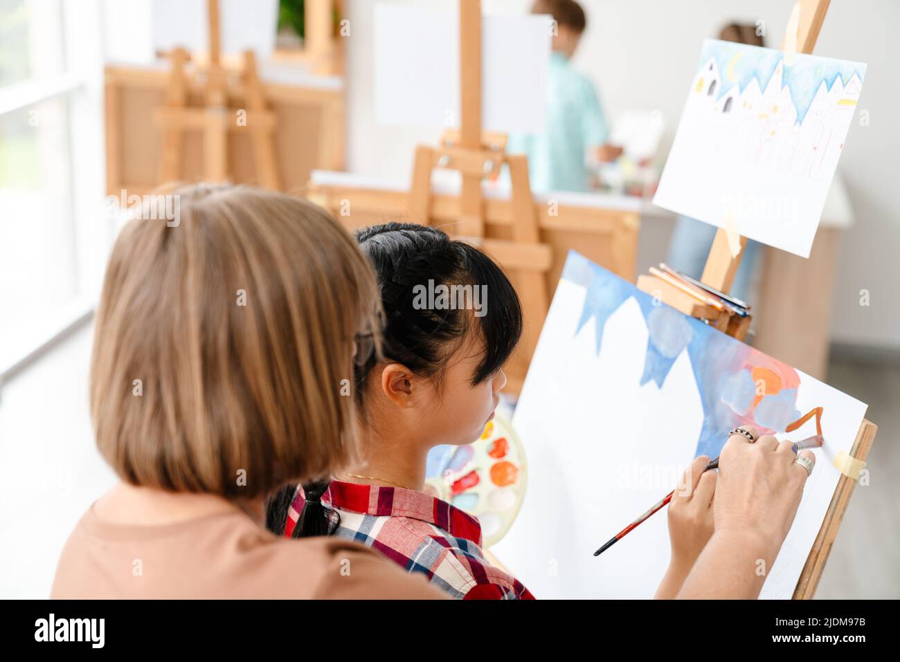 White teacher talking with her student during class in art school ...