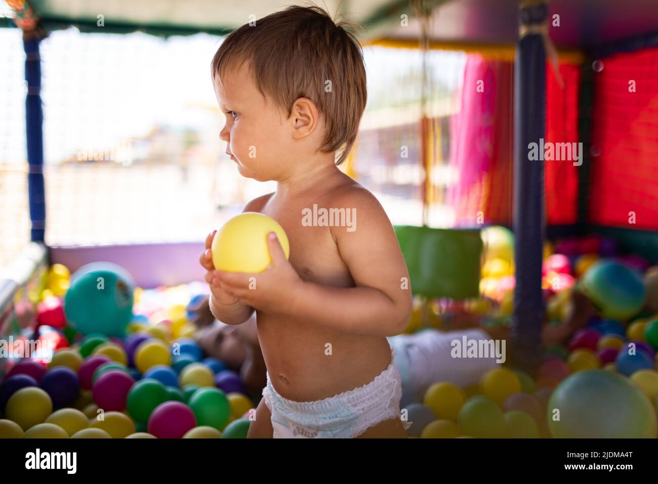 Little cheerful funny boy in a diaper with an inflatable green striped ...