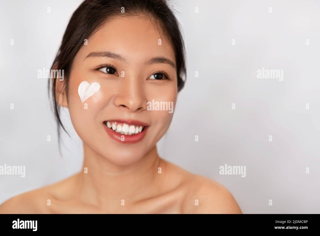 Facial skincare. Happy korean lady with heart-shaped moisturizer cream ...