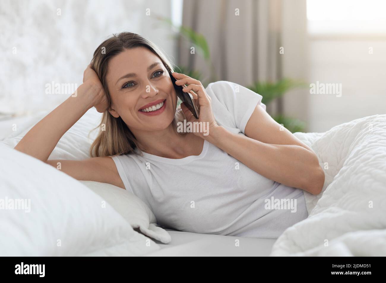 Positive pretty woman having phone call in bed Stock Photo - Alamy