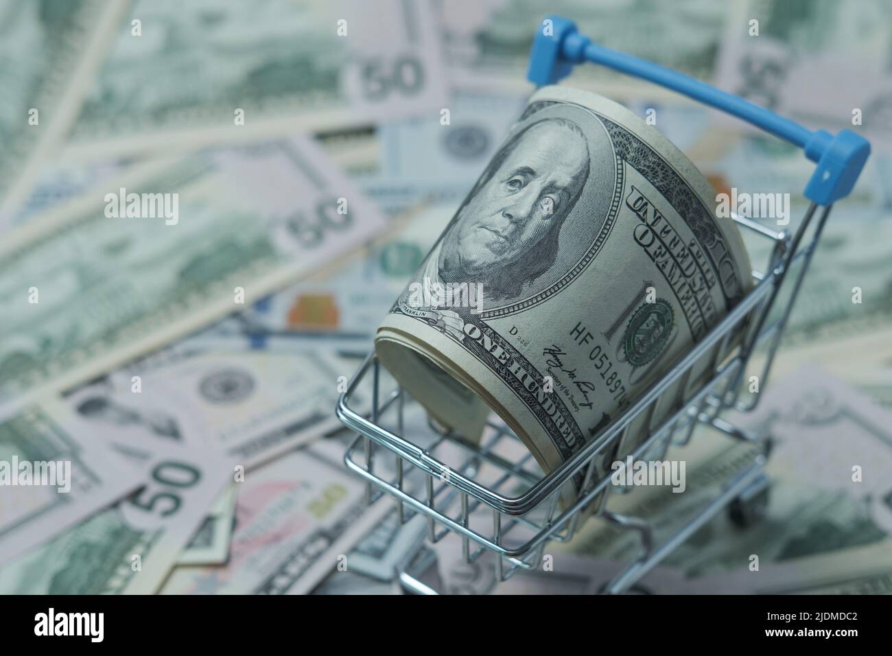 Dollars rolled into a tube lie in a grocery basket. The basket stands ...