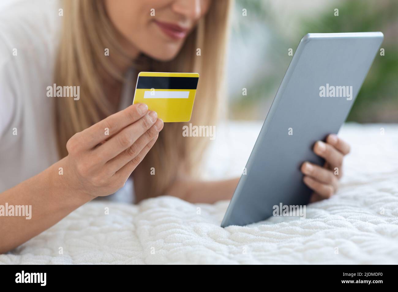 Unrecognizable woman laying in bed with tablet and credit card Stock ...