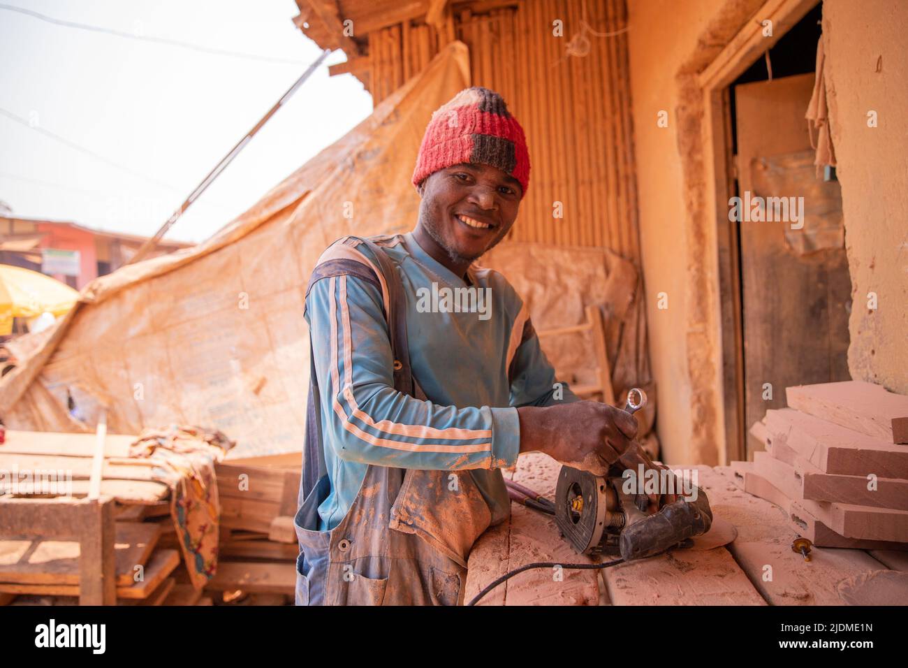 An african carpenter uses a chainsaw shaper in his workshop while ...