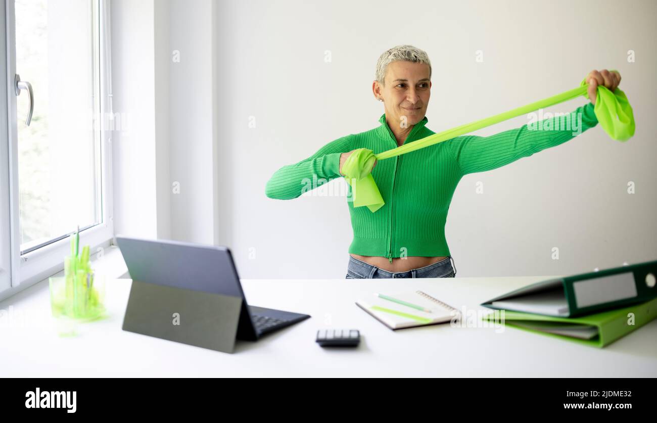 middle aged businesswoman standing at white high table in office doing ...