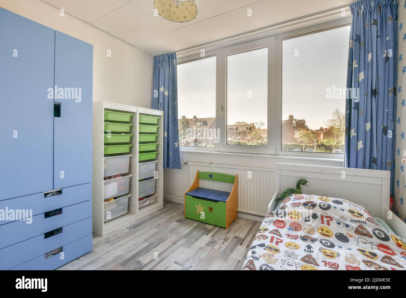 Interior of white room with children bed and blue wardope near window ...