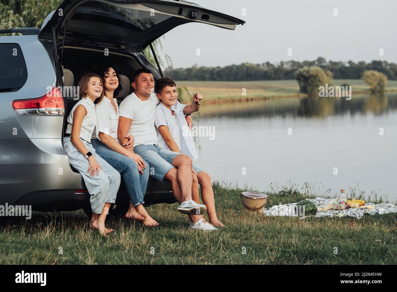 Happy Four Caucasian Members Family Sitting in Trunk of Minivan Car ...