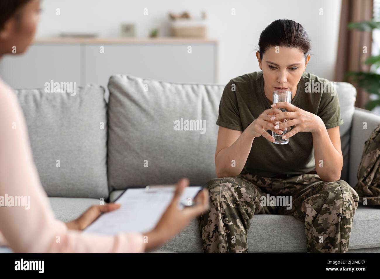 Portrait of stressed military woman at therapy session with black ...
