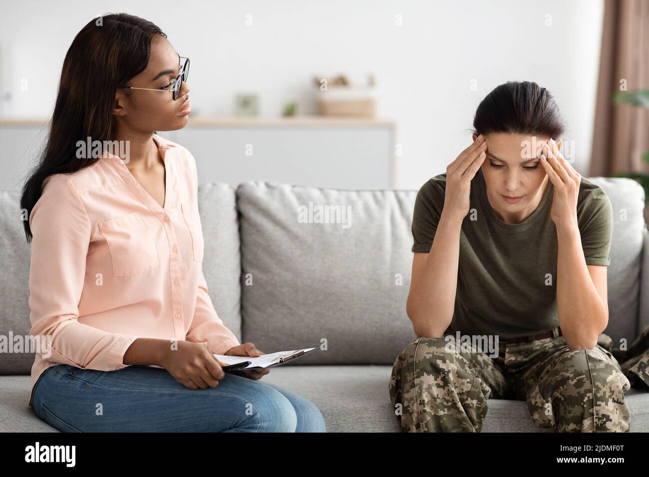 Black female psychologist talking to depressed female soldier suffering ...