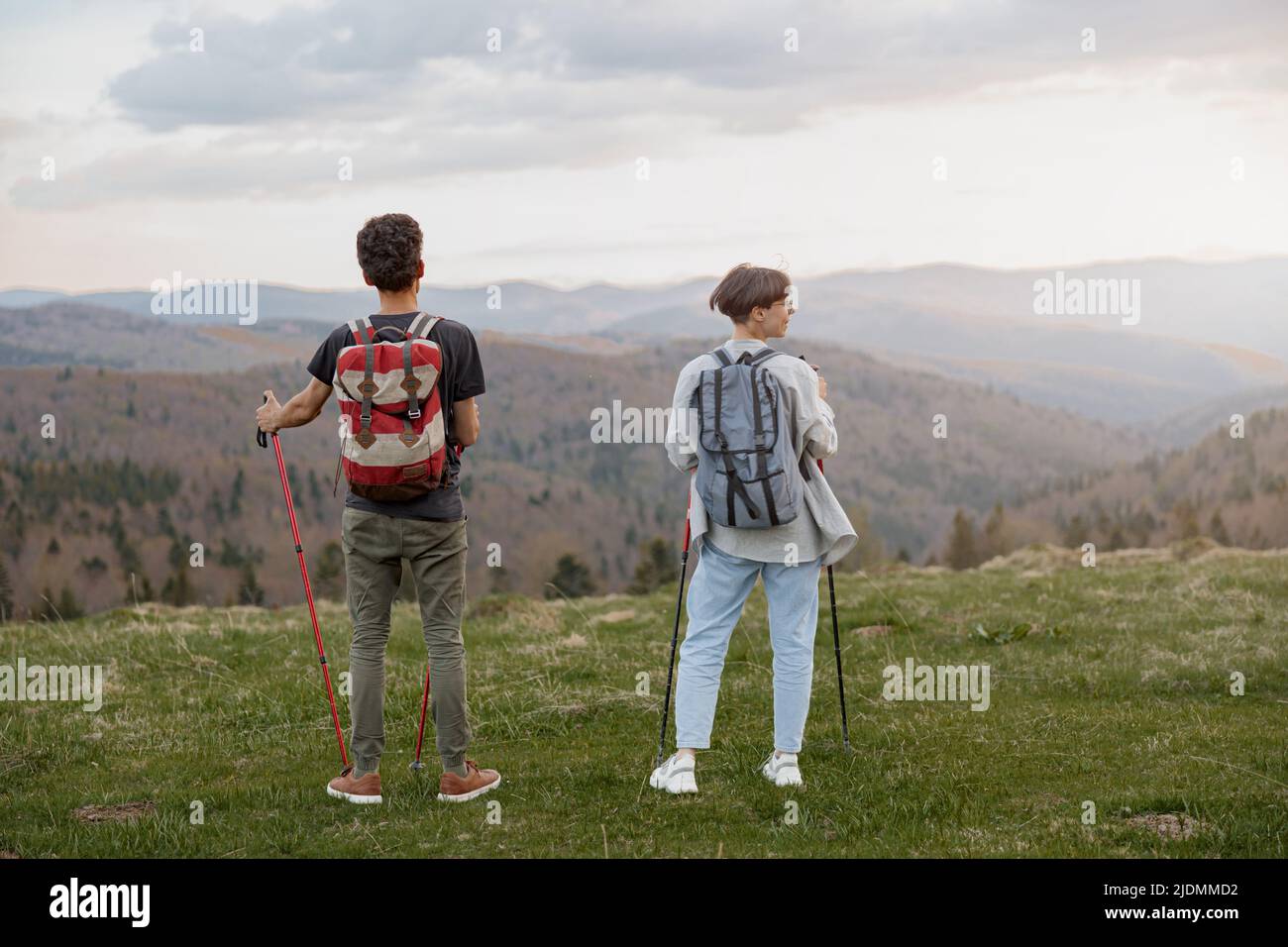 Back view on male and female hikers with walking sticks on top of ...