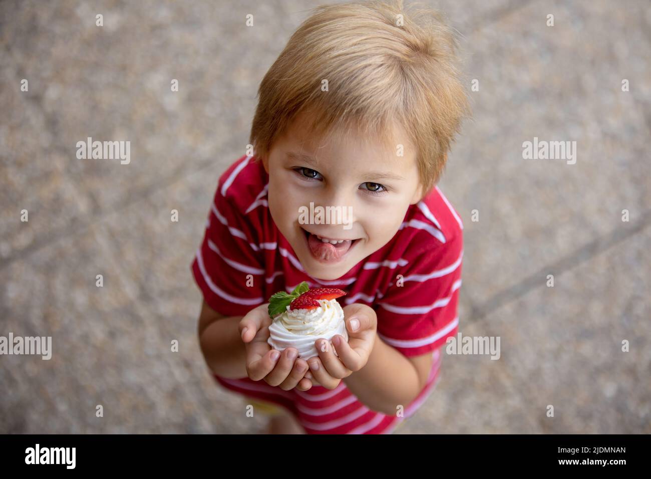 Cute child, boy, eating small cupcake of Pavlova desert, light egg and ...