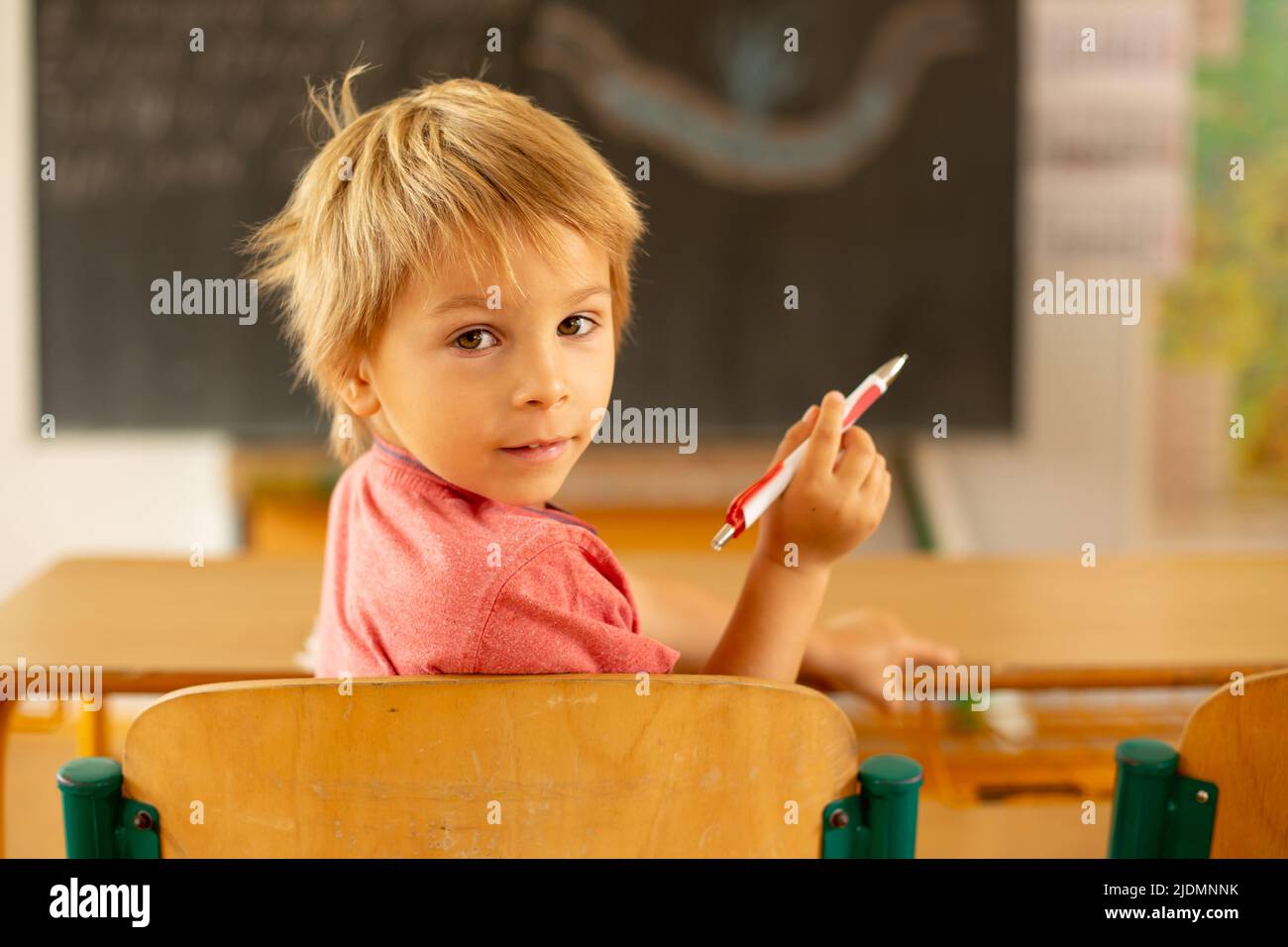 Preschool child, sitting on a desk at school, having lesson, learning ...