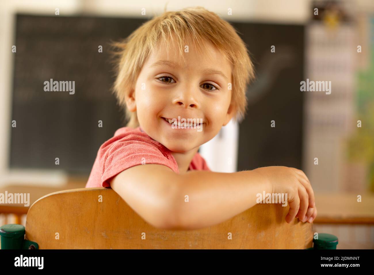 Preschool child, sitting on a desk at school, having lesson, learning ...
