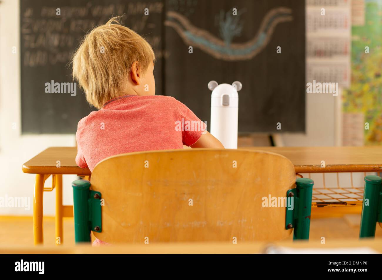 Preschool child, sitting on a desk at school, having lesson, learning ...
