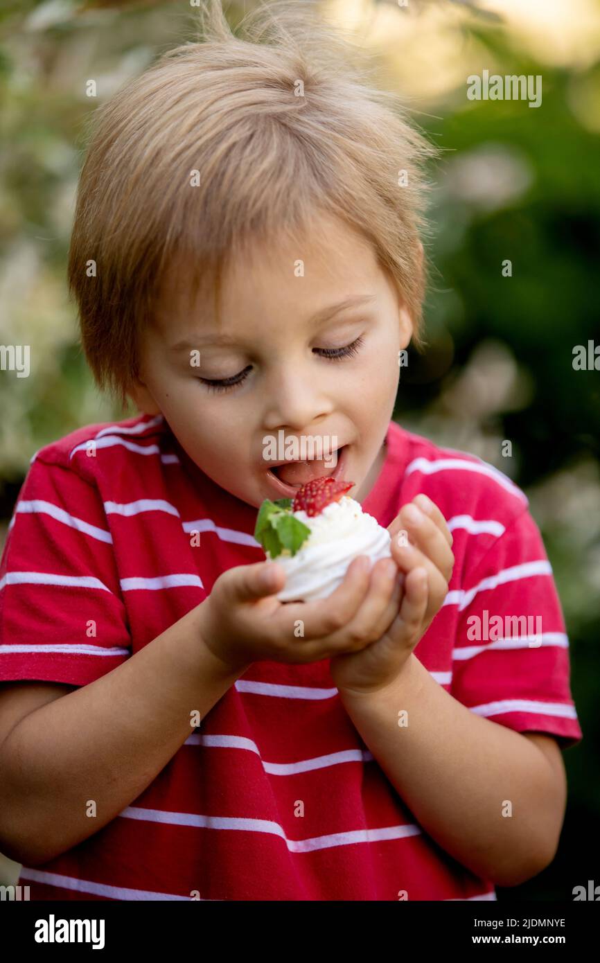 Cute child, boy, eating small cupcake of Pavlova desert, light egg and ...