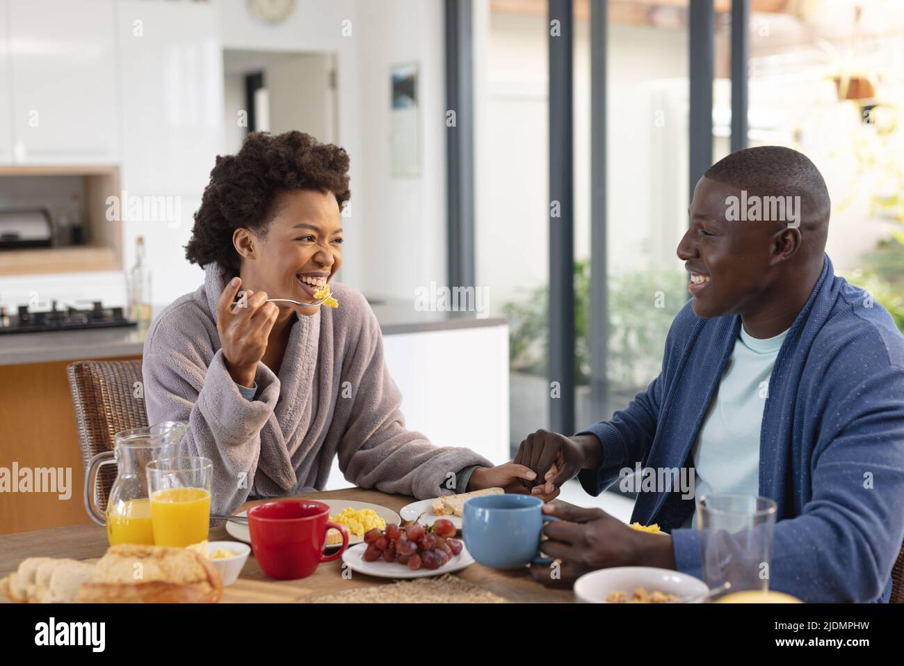 Happy african american mid adult couple holding hands while having ...