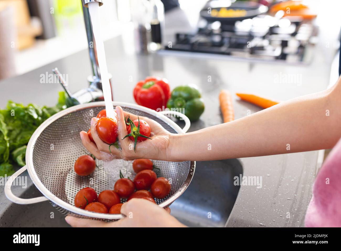 High angle midsection of asian young woman cleaning tomatoes in sink ...