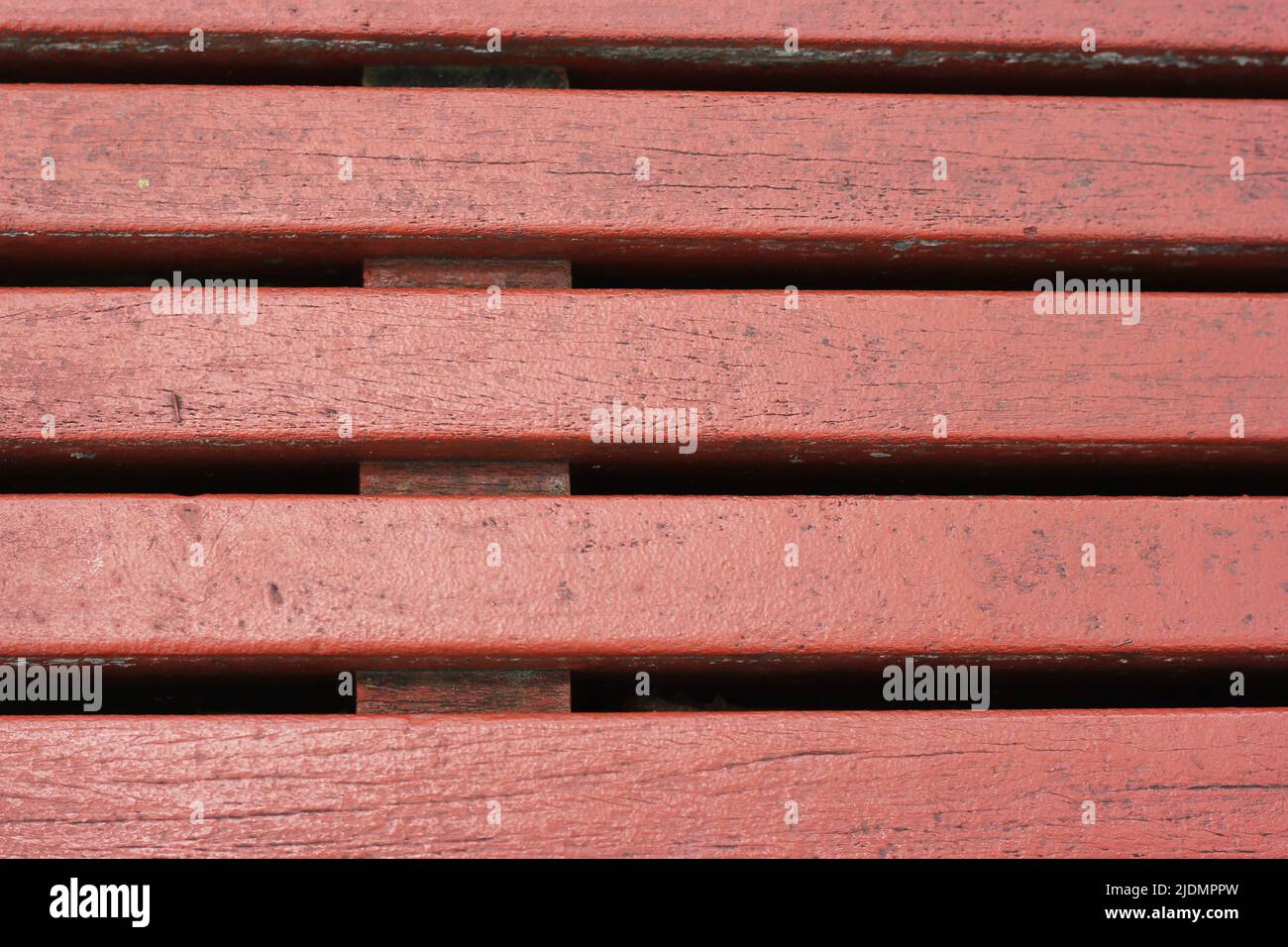 A full frame closeup of a wooden bench with red horizontal lines and ...